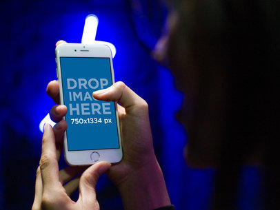 Placeit - Woman Holding a White iPhone Mockup Against a Wall with Neon ...