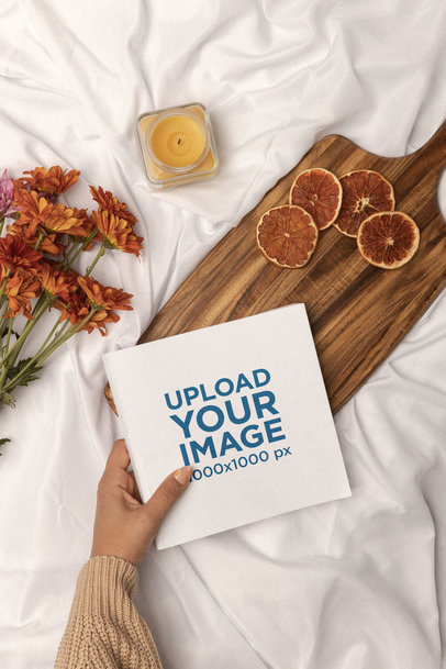 Placeit - Mockup of a Square Book Being Placed on a Cute Aesthetic Setting