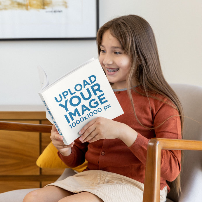 Placeit - Mockup of a Girl Reading a Square Book at Home