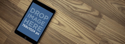 Placeit - Tablet Mockup of a Black iPad Lying on Hardwood Floor