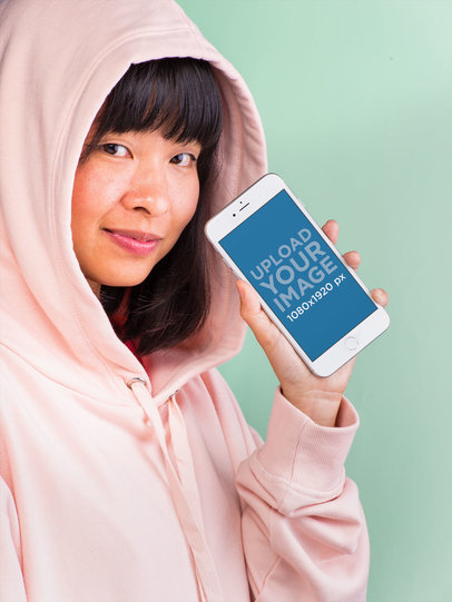 Placeit - Mockup of a Woman Showing an iPhone 8 Plus Wearing a Pink Hoodie