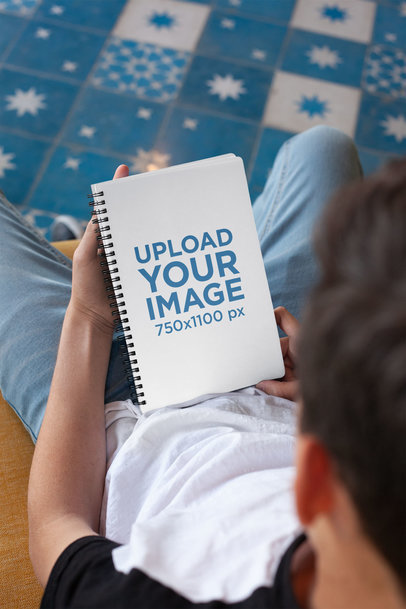 Placeit - Mockup of a Notebook Held by a Brunette Boy