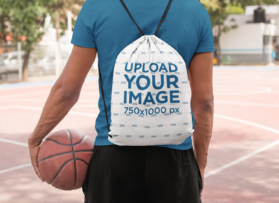 Placeit - Mockup of a Man With a Drawstring Bag in a Basketball Court