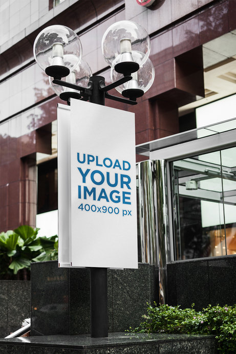 Placeit - Mockup of a Banner Sign Attached to a Post Outside a Building
