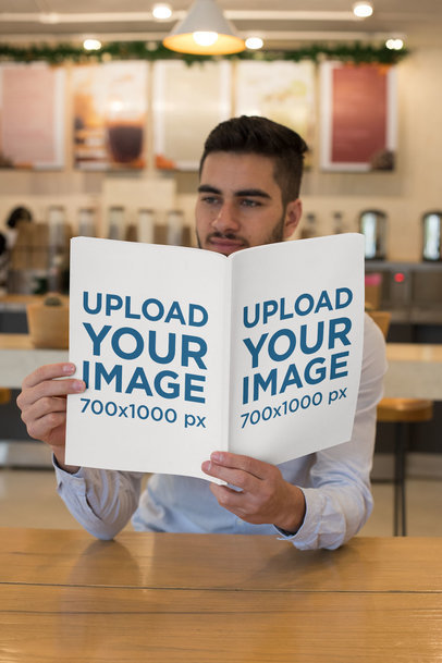 Placeit - Mockup of a Young Man Reading a Magazine at a Coffee Shop