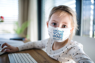 Placeit - Face Mask Mockup of a Little Girl Using a Computer