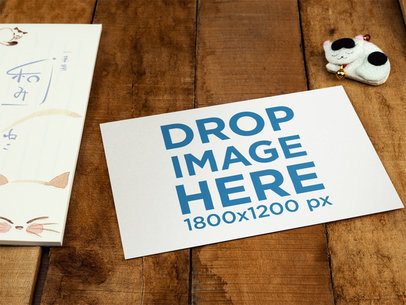 Placeit - Postcard Template Lying on a Wooden Table Near a Kitten Nearby
